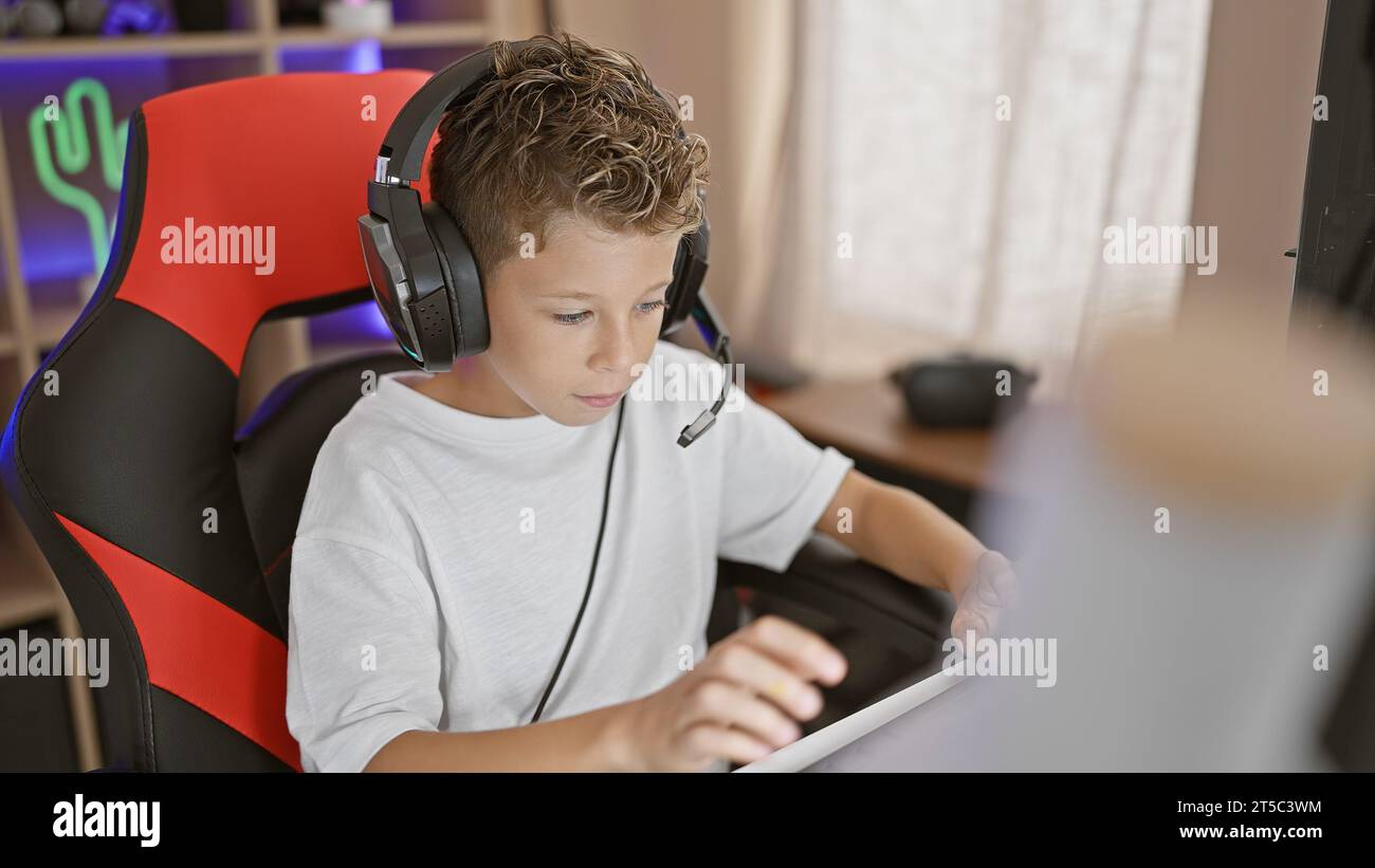 Blond boy streamer playing video game using computer at gaming room ...