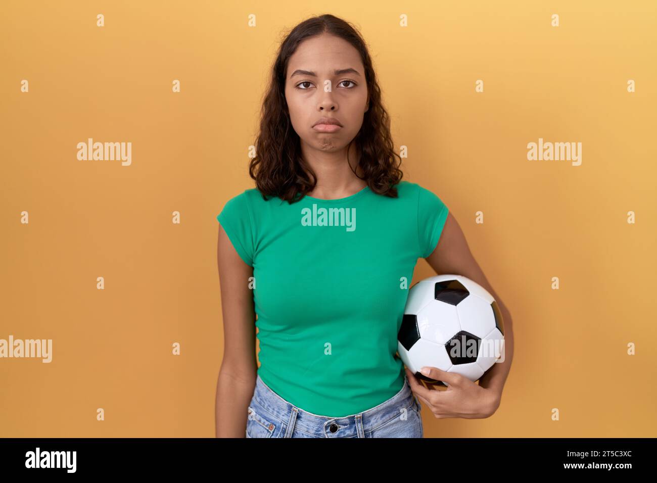 Young hispanic woman holding ball depressed and worry for distress ...