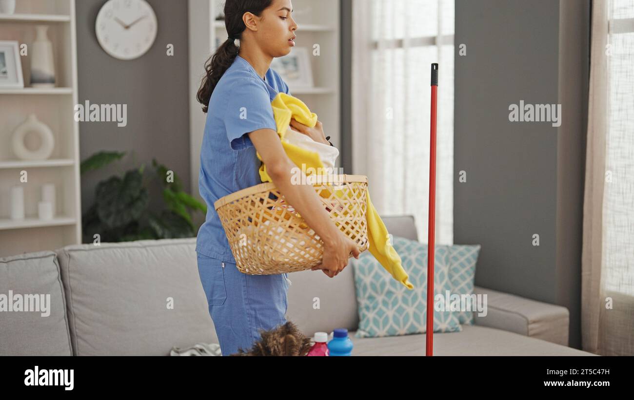 African american woman professional cleaner collecting clothes at home ...