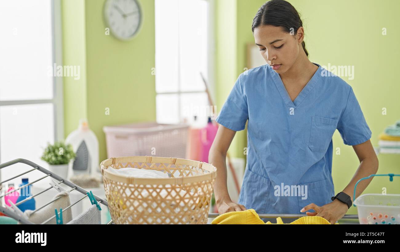 African american woman professional cleaner hanging clothes on ...