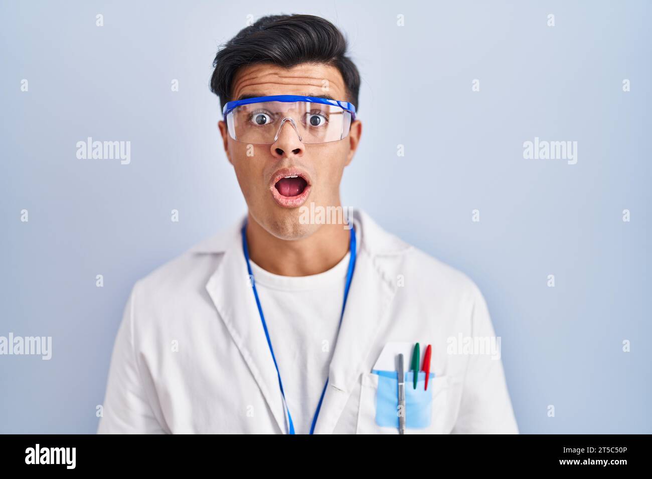 Hispanic man working as scientist afraid and shocked with surprise ...