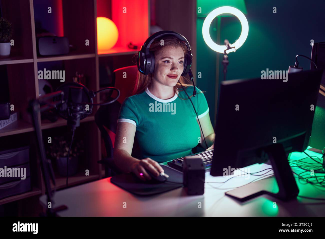 Young redhead woman streamer playing video game using computer at ...