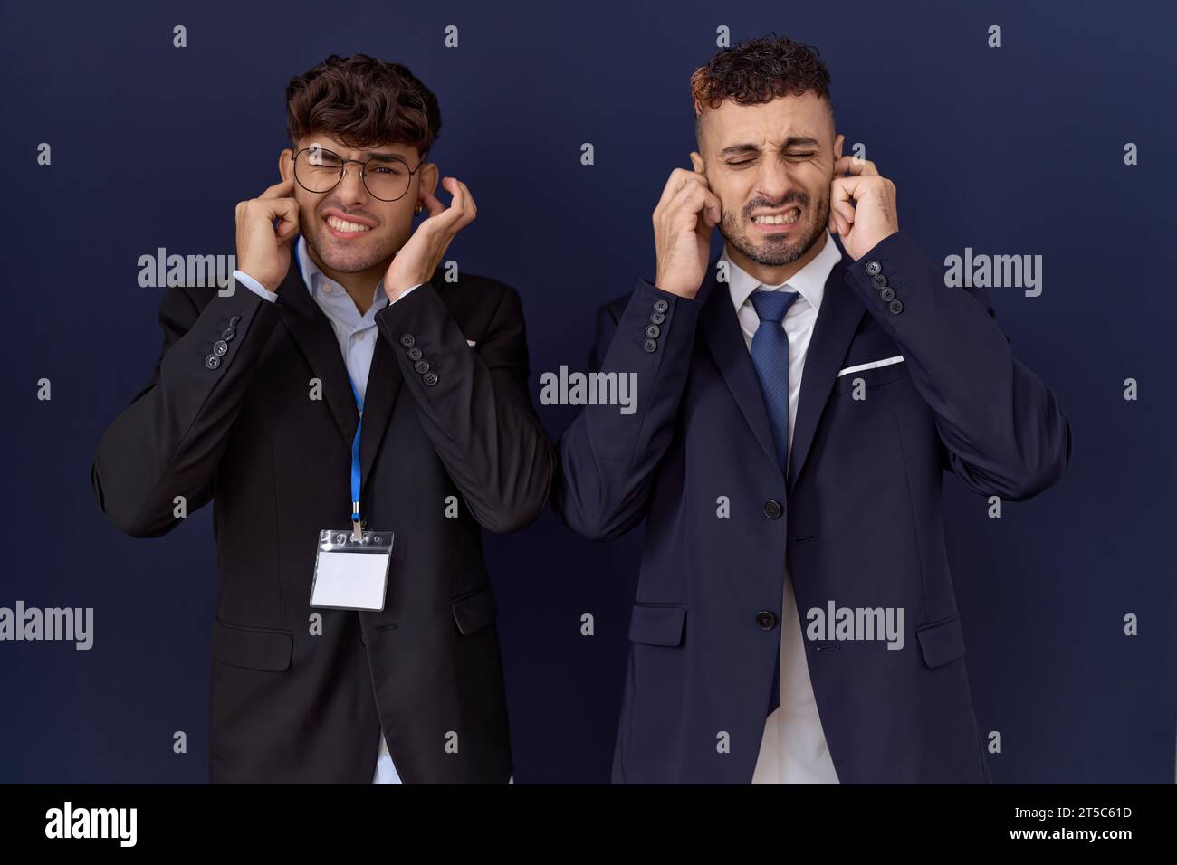 Two hispanic business men wearing business clothes covering ears with ...