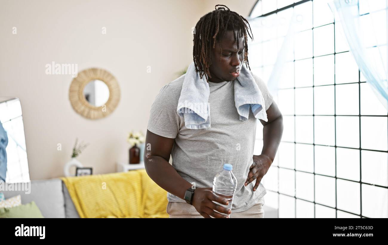 African american man standing with serious face tired holding bottle of ...