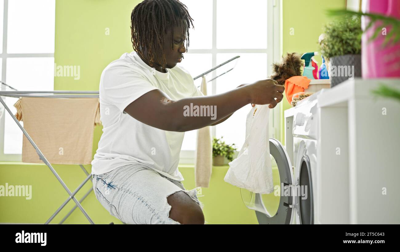 African american man washing clothes holding dirty t shirt at laundry ...