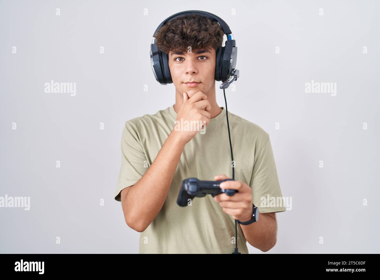 Hispanic teenager playing video game holding controller looking ...