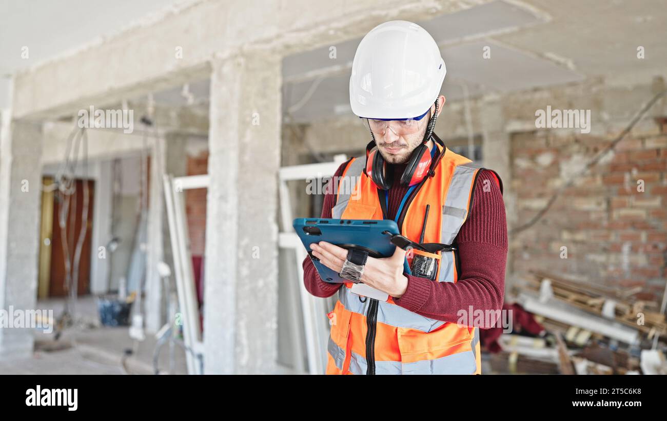 Young hispanic man builder using touchpad at construction site Stock ...