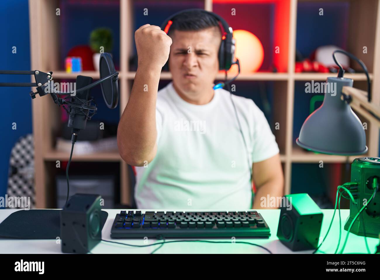 Young hispanic man playing video games angry and mad raising fist ...