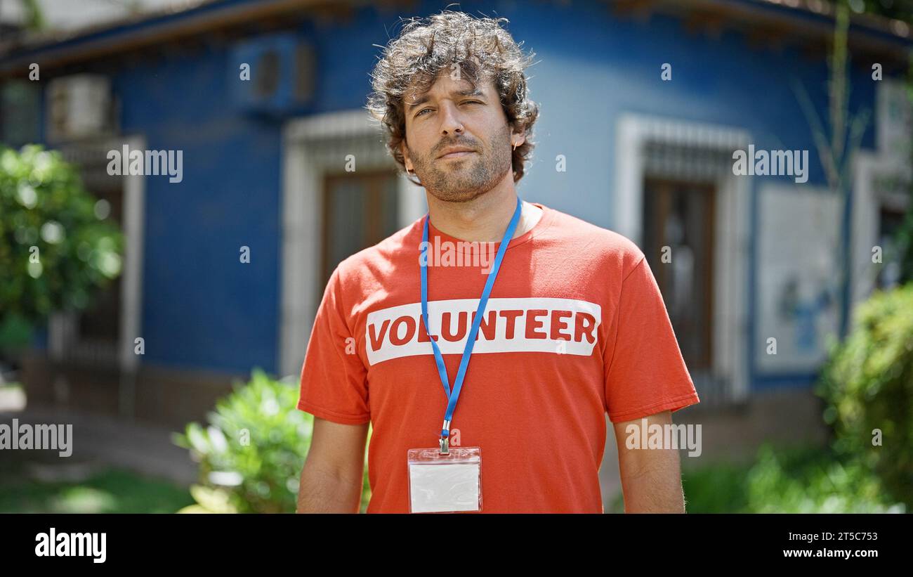 Young hispanic man activist wearing volunteer uniform standing with ...