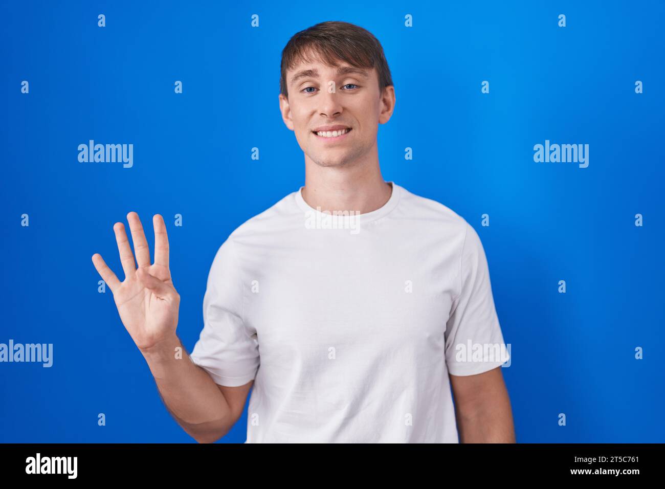 Caucasian blond man standing over blue background showing and pointing ...