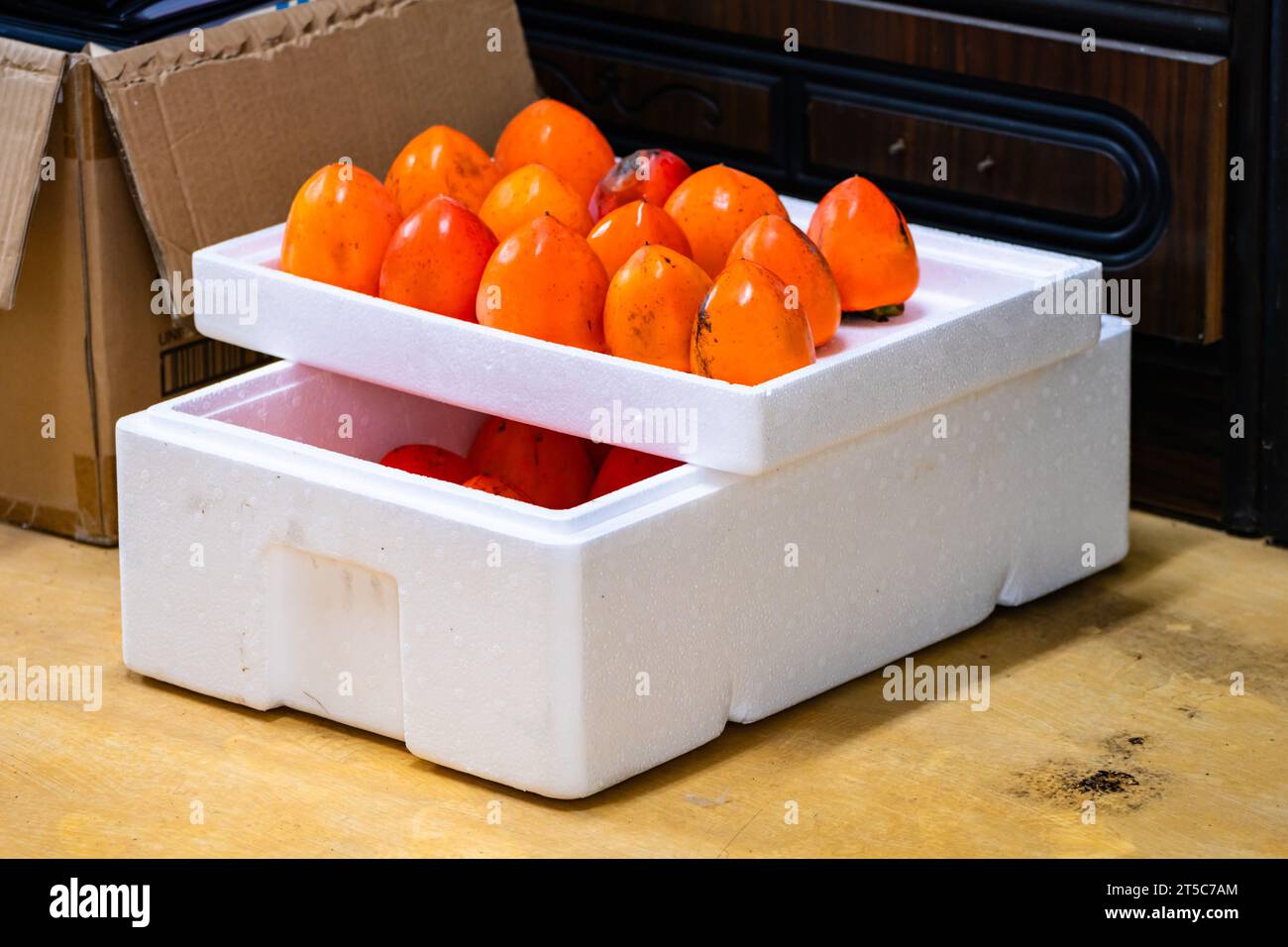 Sweet persimmons that were harvested were collected in a white ...