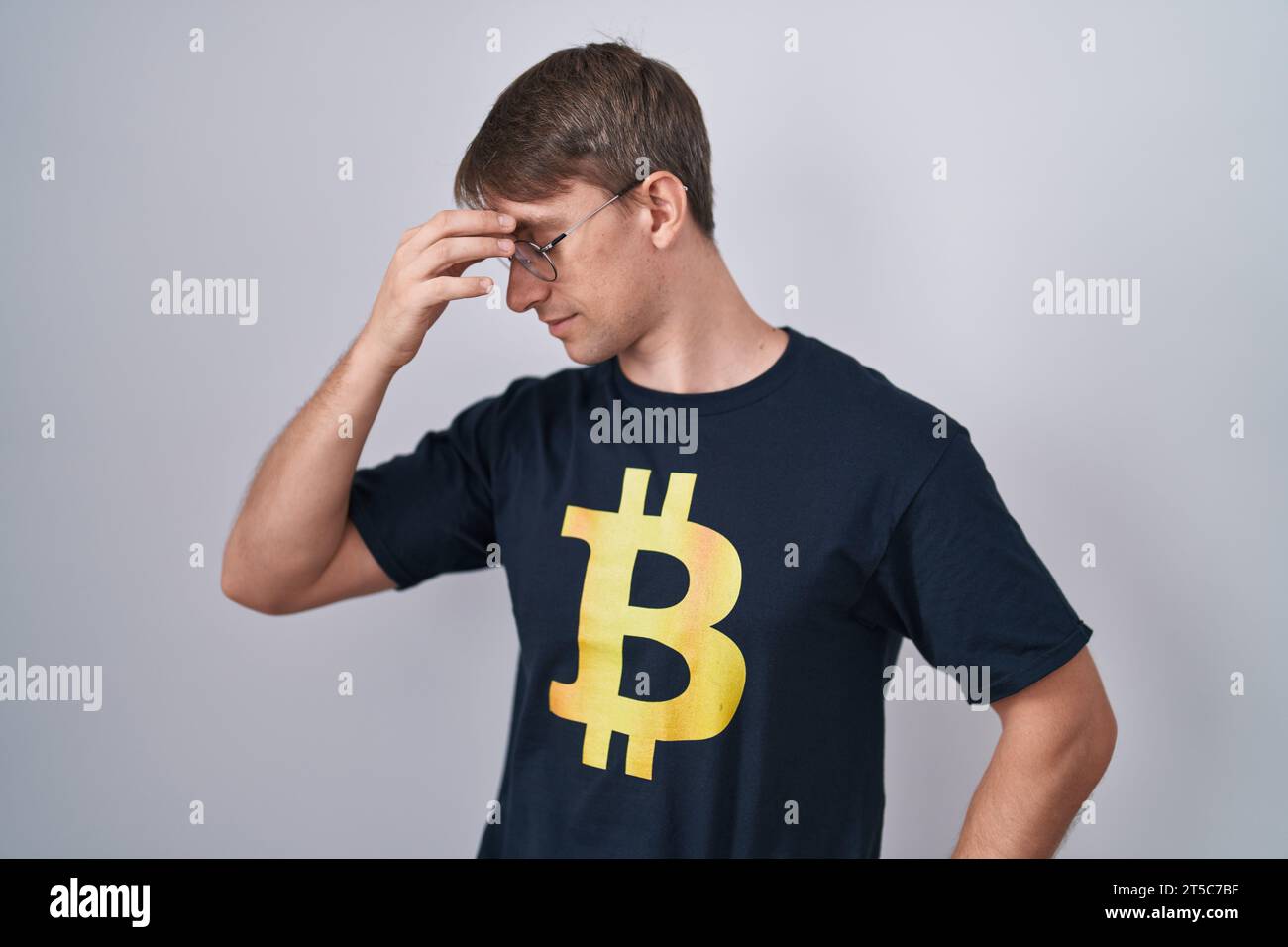 Caucasian blond man wearing bitcoin t shirt tired rubbing nose and eyes ...