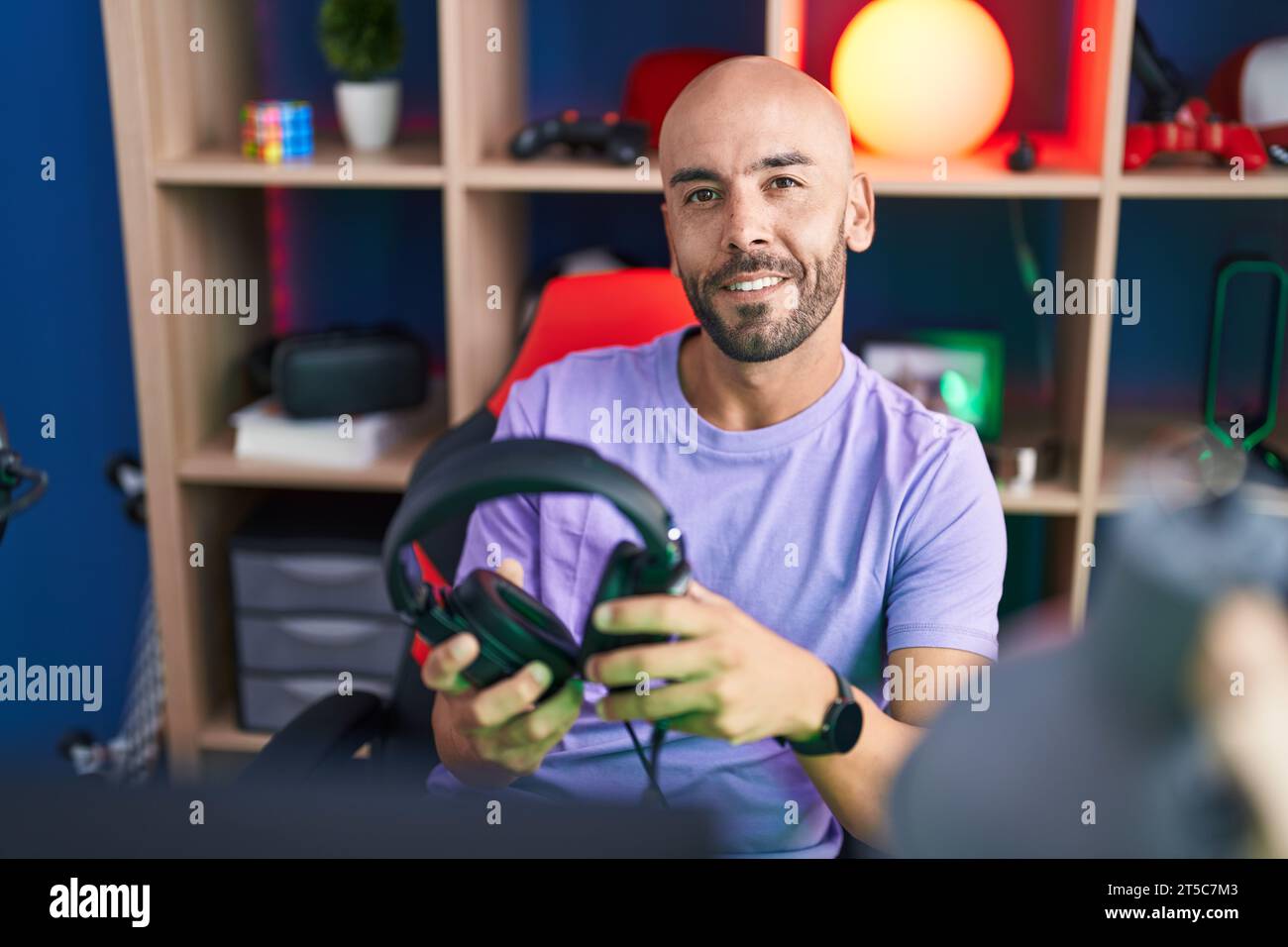 Young bald man streamer smiling confident holding headphones at gaming ...