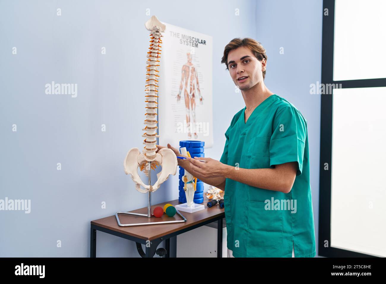 Young caucasian man physiotherapist touching anatomical model of spinal ...