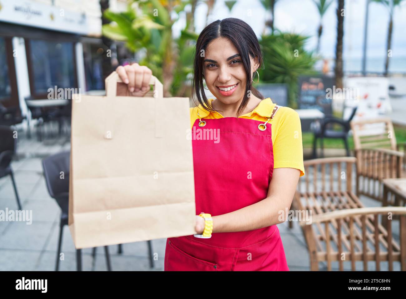 Young beautiful arab woman waitress smiling confident holding take away ...