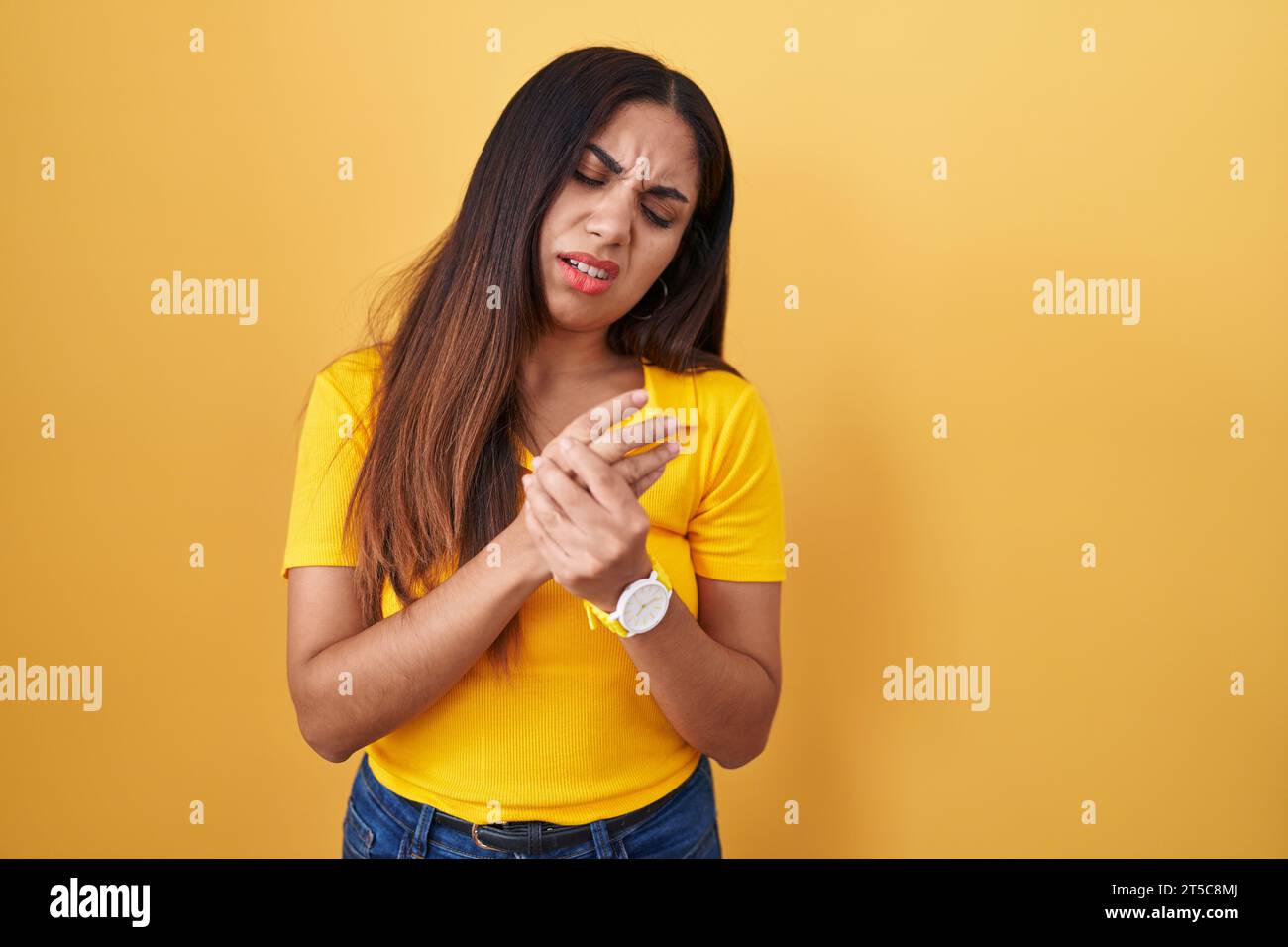 Young arab woman standing over yellow background suffering pain on ...