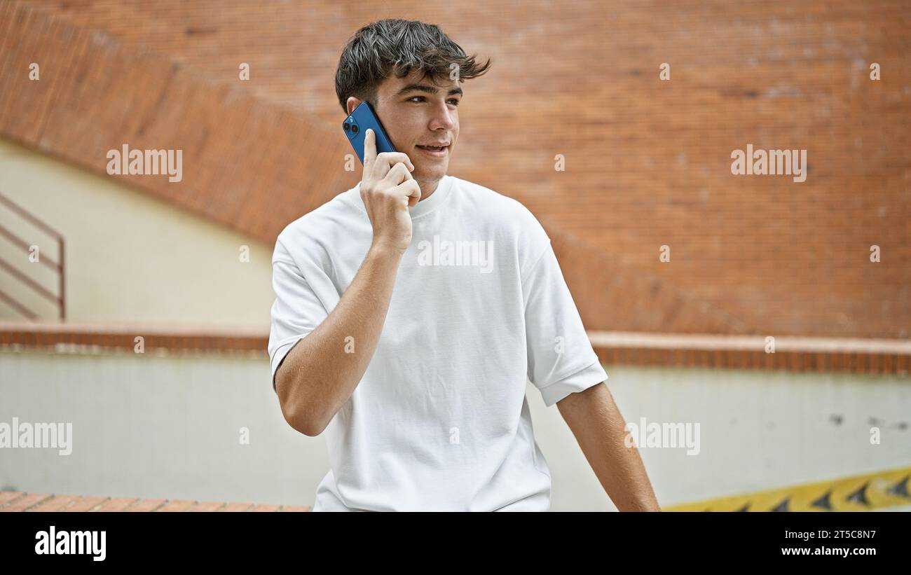 Casual young hispanic male, engrossed in serious phone talk on a sunlit ...