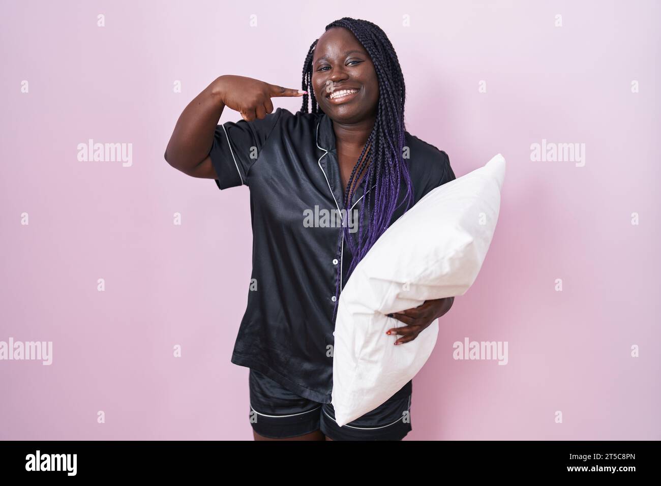 Young african woman wearing pijama hugging pillow smiling cheerful ...