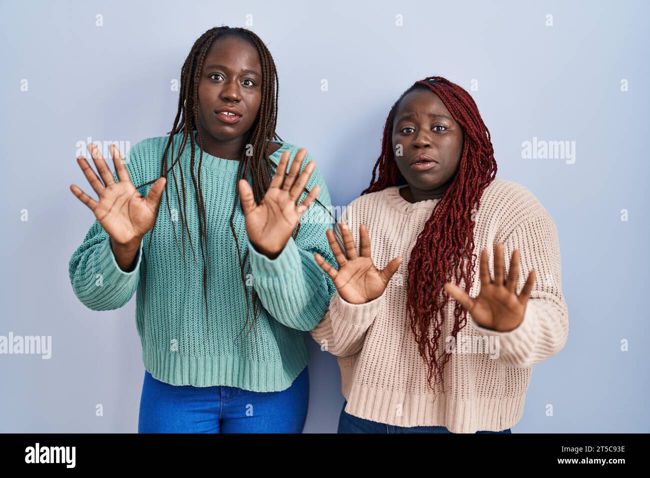 Two african woman standing over blue background moving away hands palms ...