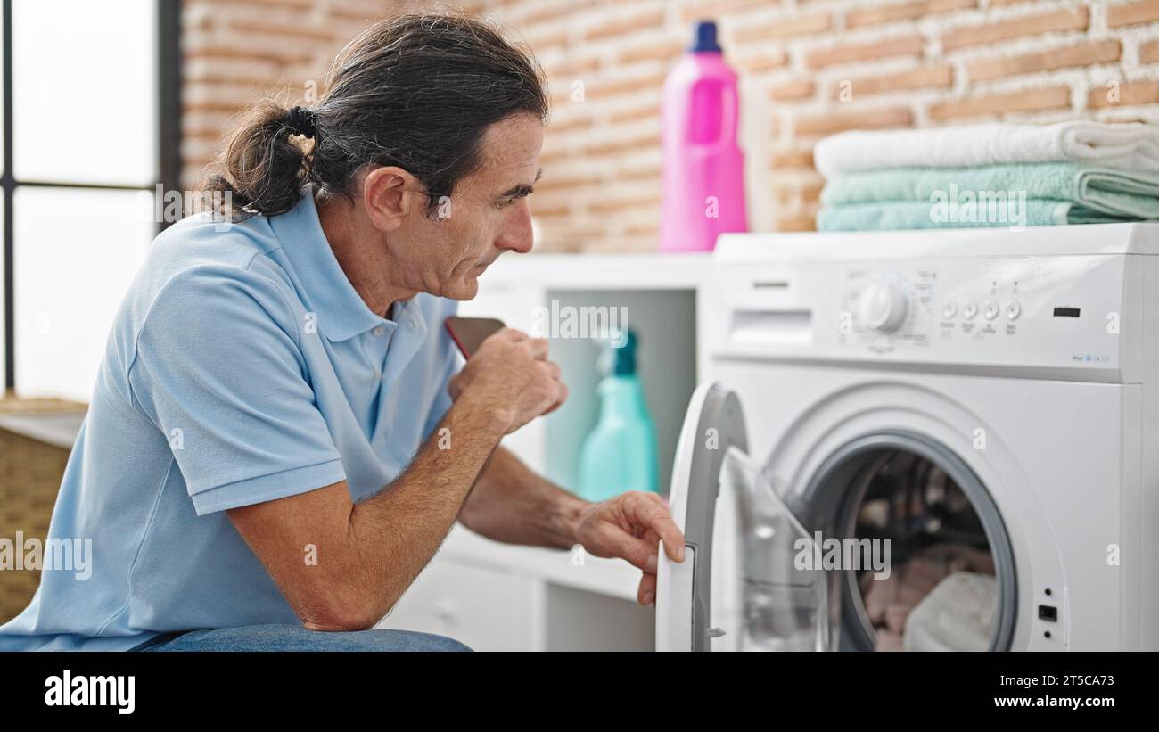 Middle age man washing clothes at laundry room Stock Photo - Alamy