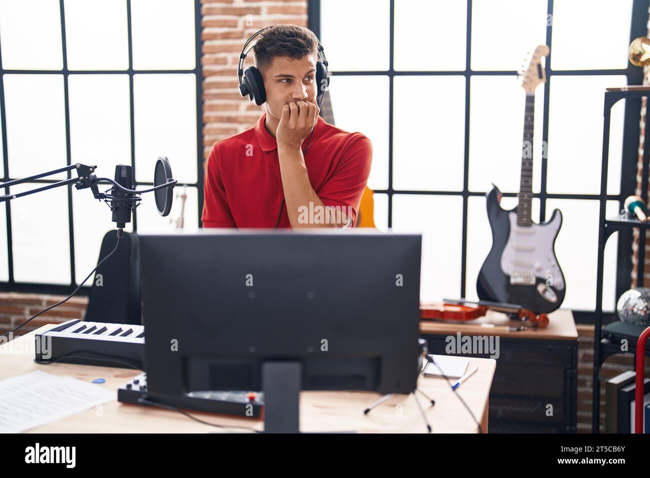 Young hispanic man playing piano keyboard at music studio looking ...