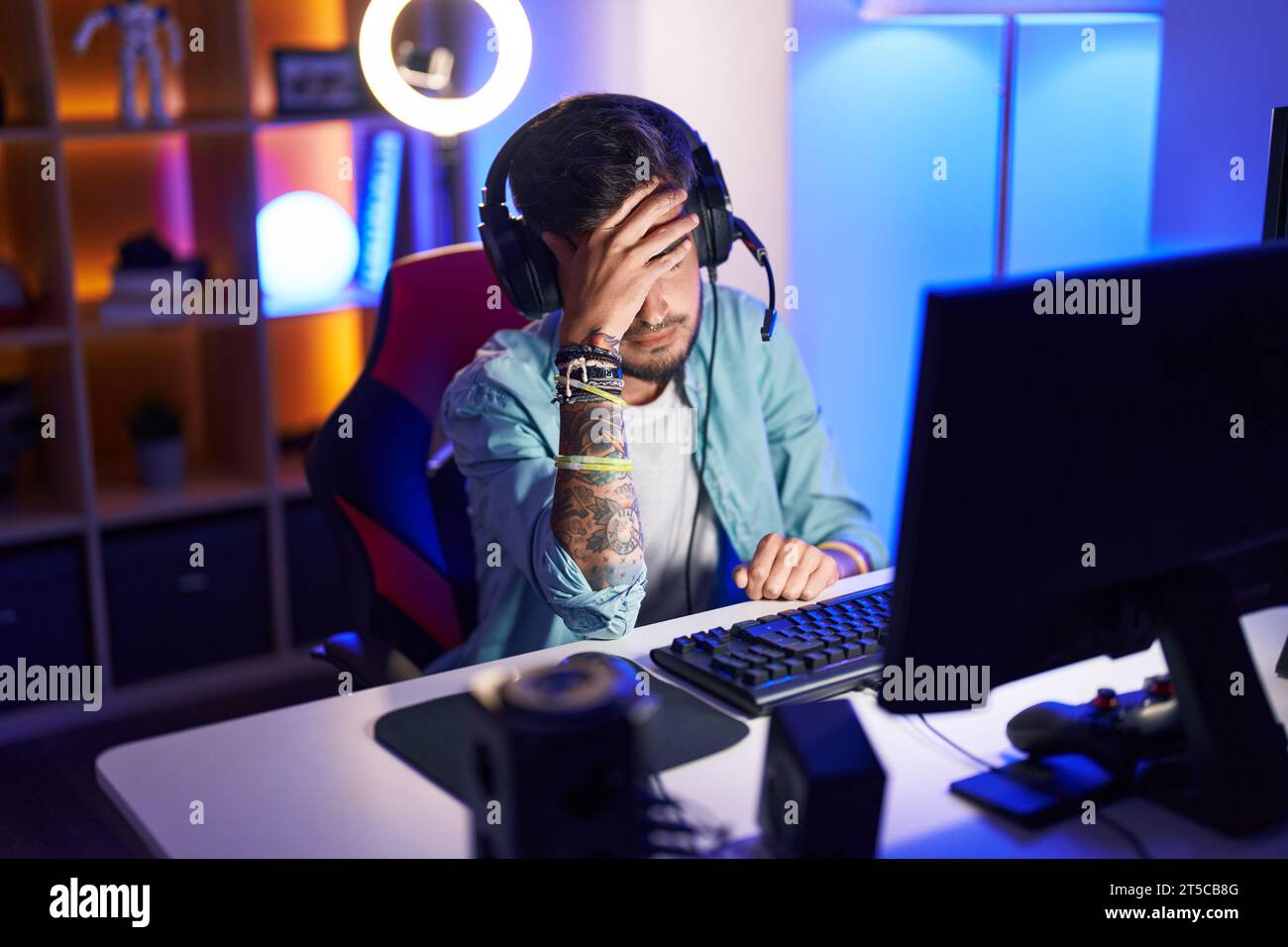 Young hispanic man streamer stressed using computer at gaming room ...