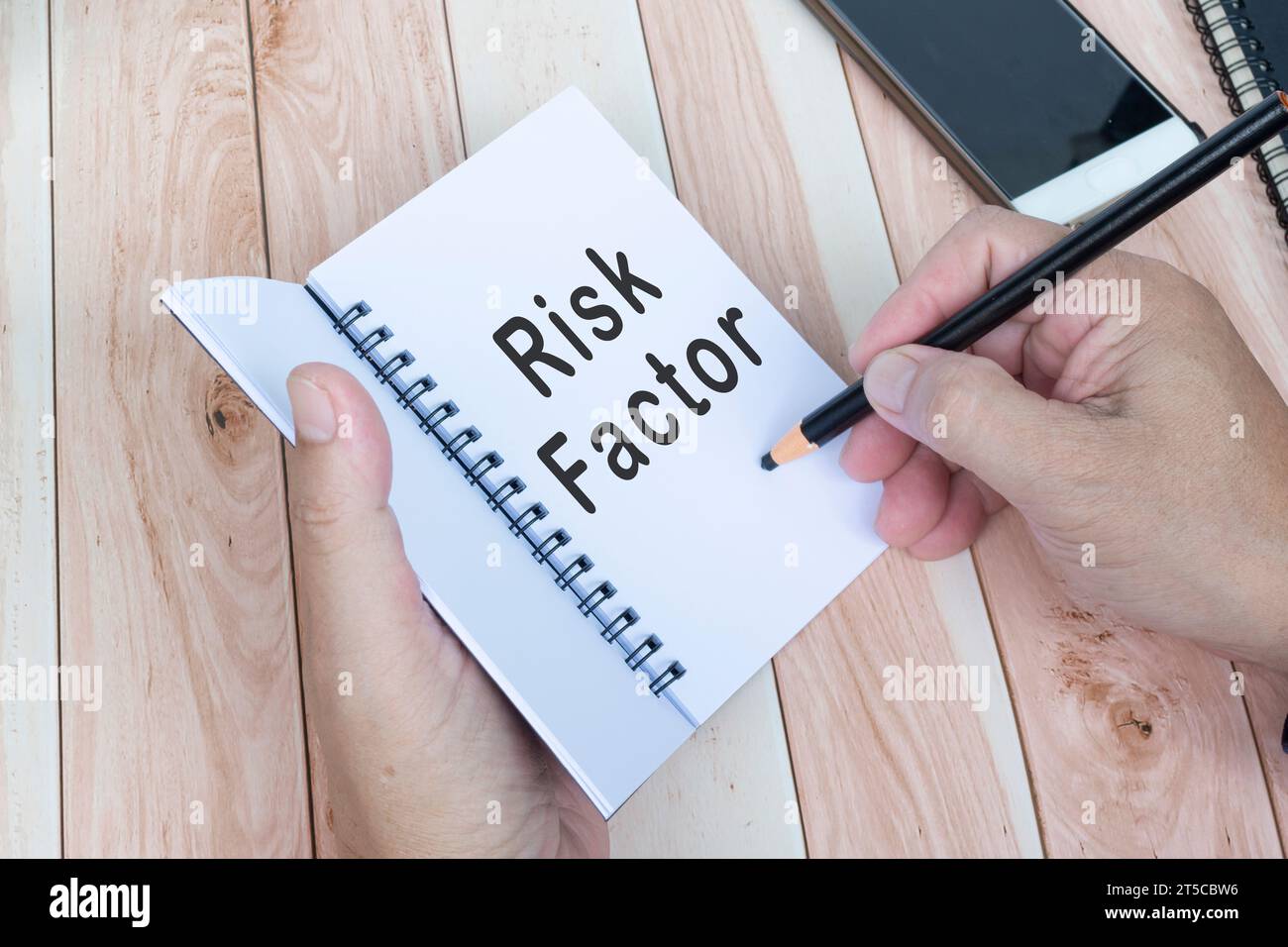 Businessman hands with pen writing notebook on office desk. Risk Factor ...