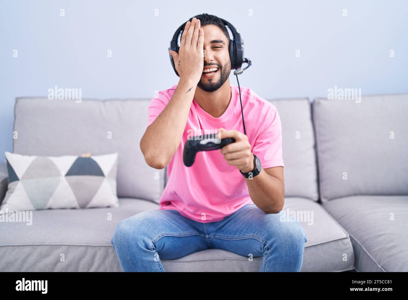 Hispanic young man playing video game holding controller sitting on the ...
