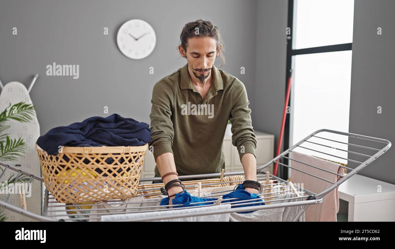 Young hispanic man hanging clothes on clothesline at laundry room Stock ...
