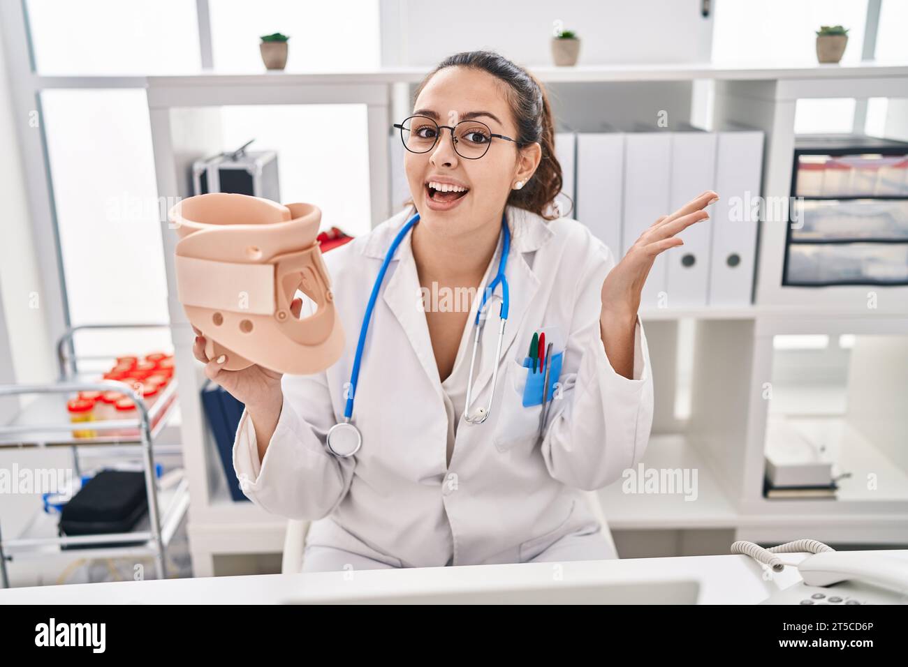 Young hispanic doctor woman holding cervical neck collar celebrating ...