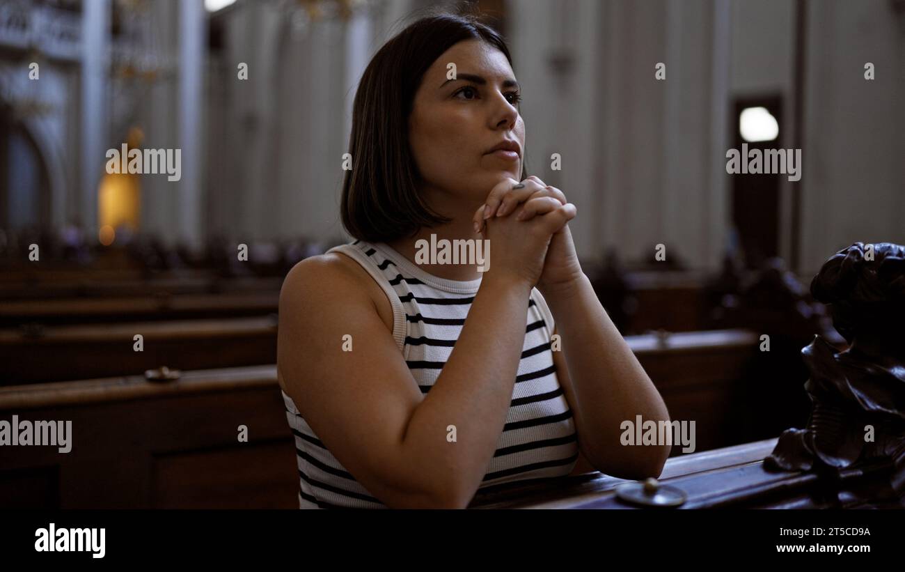 Young beautiful hispanic woman praying on a church bench at Augustinian ...