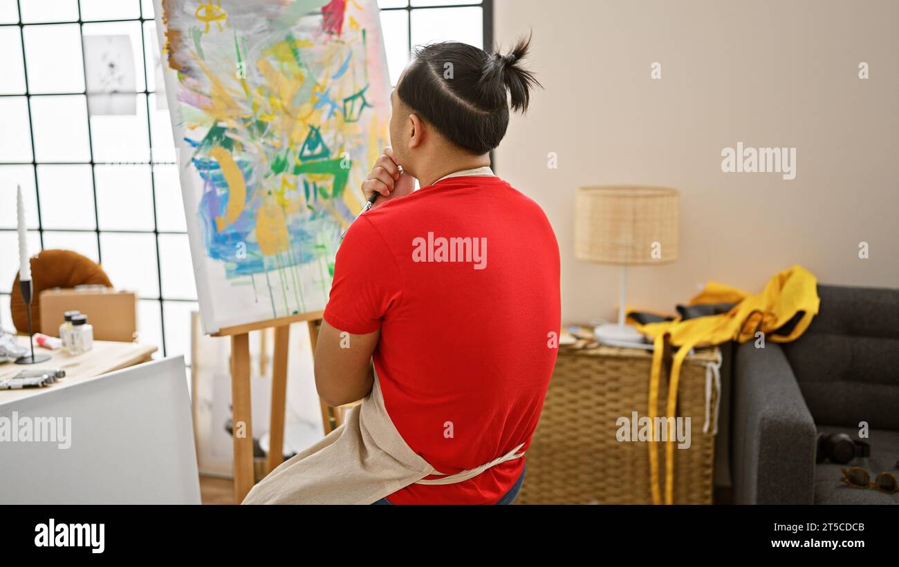 Steeped in thought, young chinese man artist, ensconced in his art ...