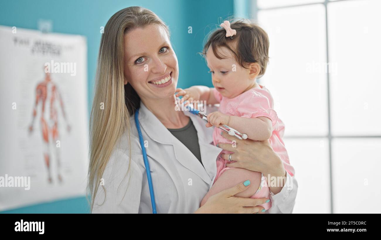 Mother and daughter pediatrician holding baby patient on arms at clinic ...
