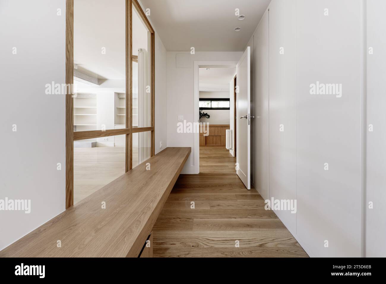 Hallway of a home with white wooden built-in wardrobes, a long wooden ...