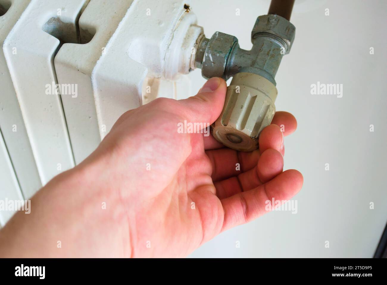 Hand closing the valve of a hot water radiator. Energy conservation ...