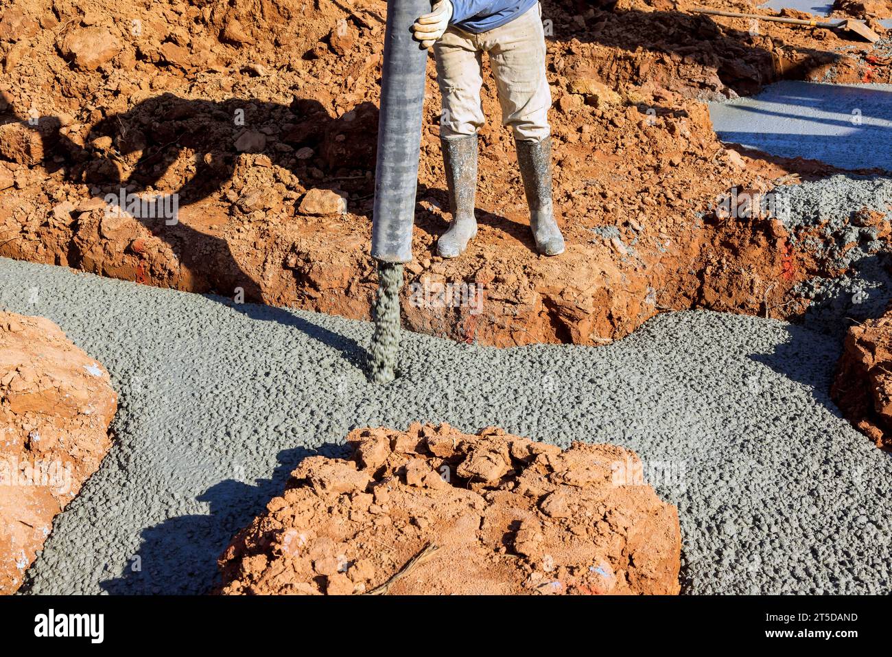 Worker at construction site pouring spreading concrete mix new house ...