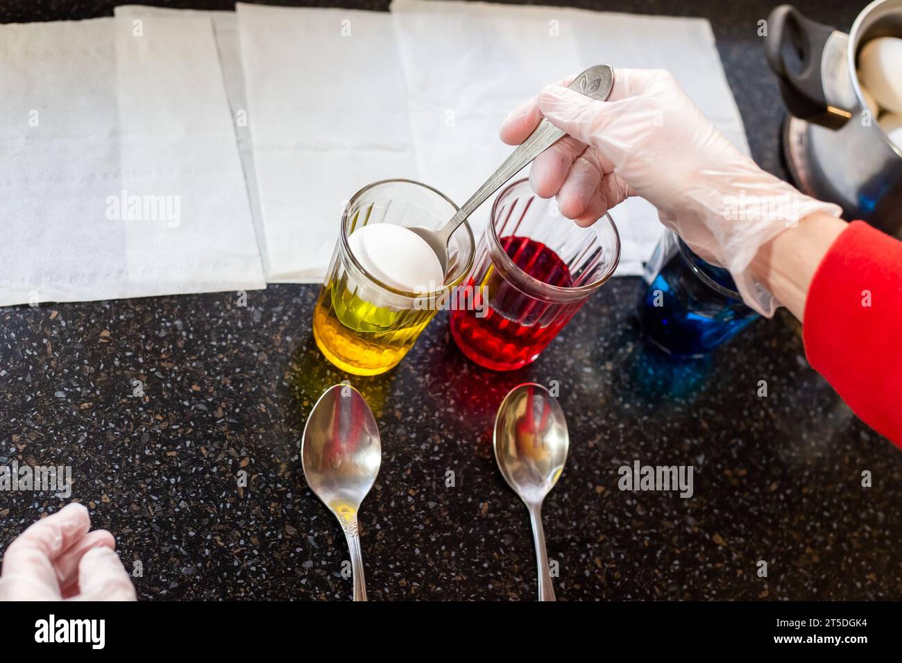 A woman dyes chicken eggs in multi-colored food dyes. Preparing for the ...