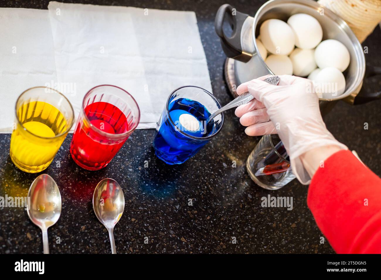 A woman dyes chicken eggs in multi-colored food dyes. Preparing for the ...