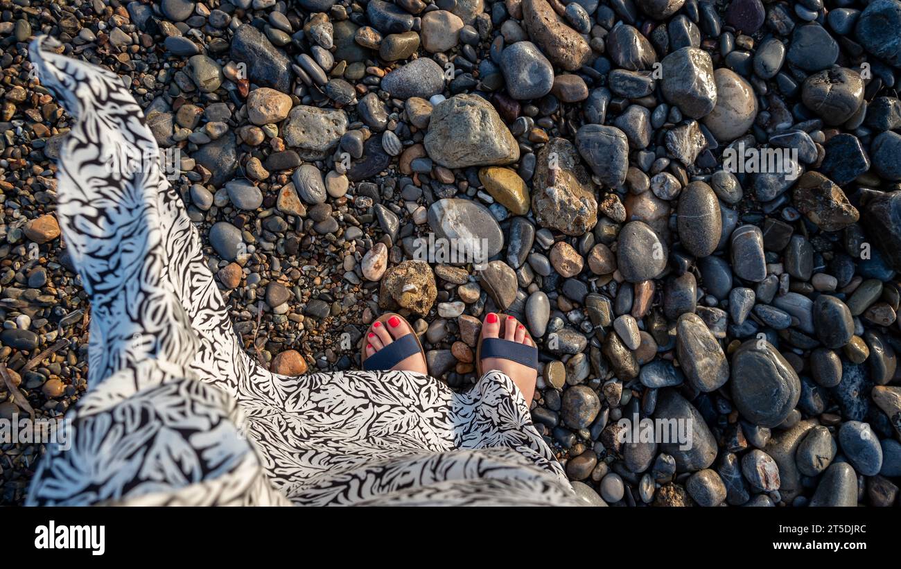 Top view of female legs, on a stone beach. The bottom of the white and ...