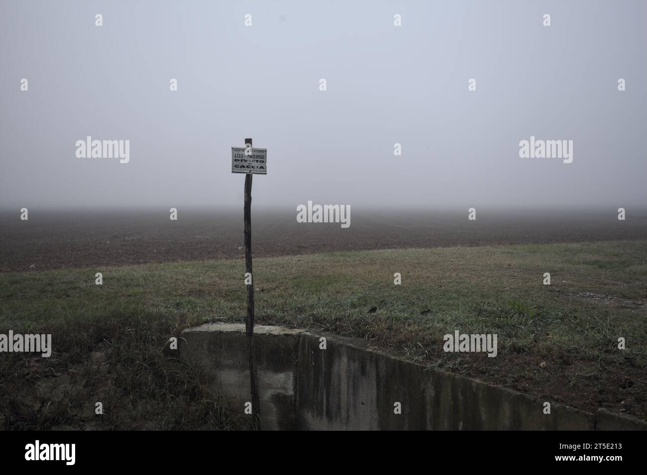 Entrance to a field with a sign over a trench on a foggy day in the ...