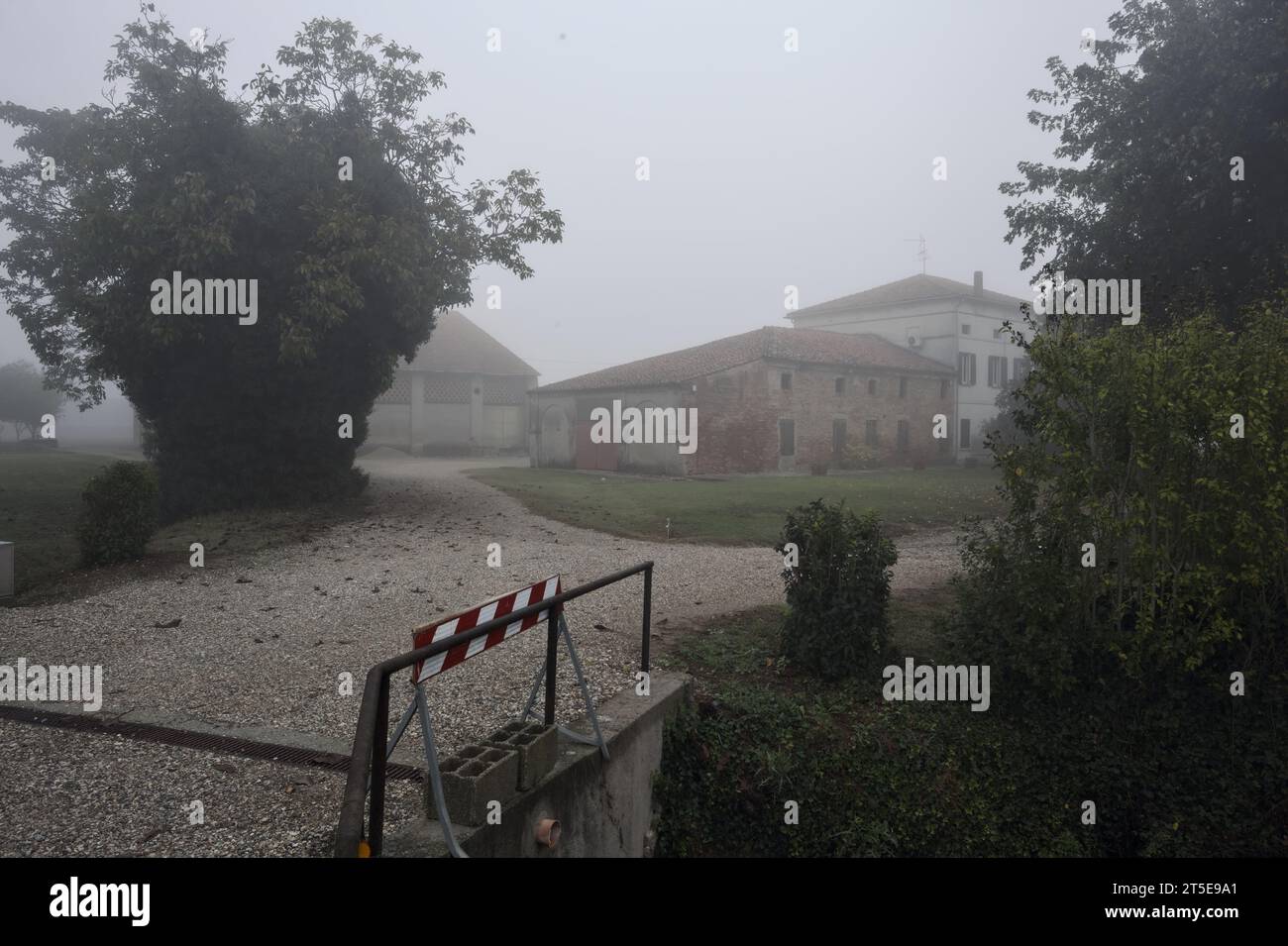 Manor and its barn with trees on a foggy day in the italian countryside ...