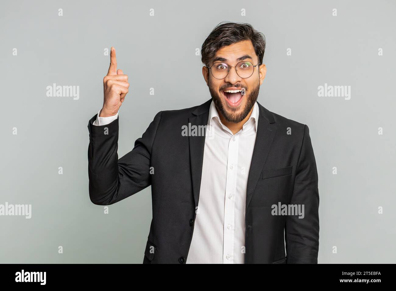 Eureka. Inspired Indian businessman pointing finger up with open mouth ...