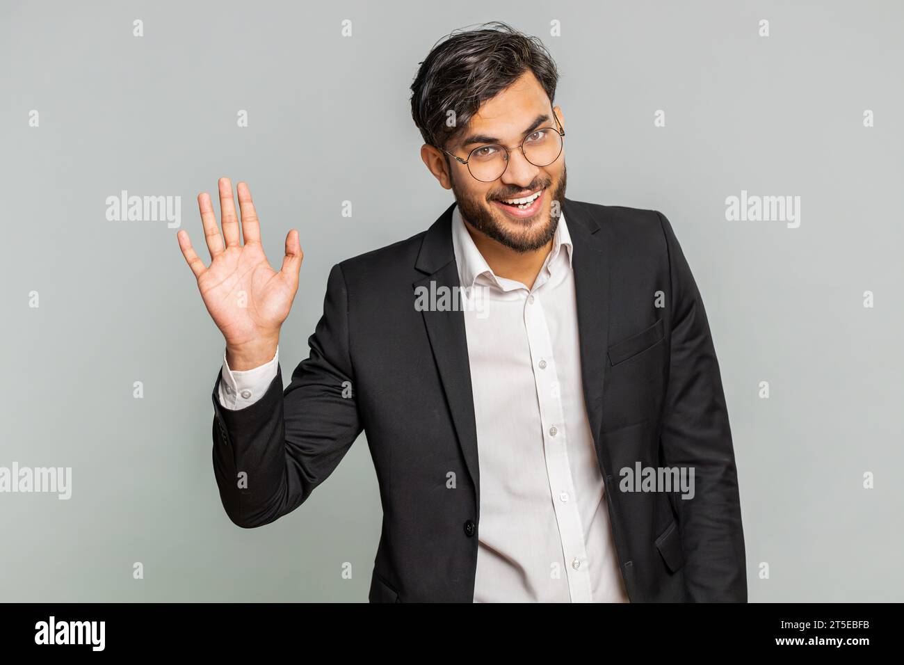 Indian businessman smiling friendly at camera, waving hands gesturing ...