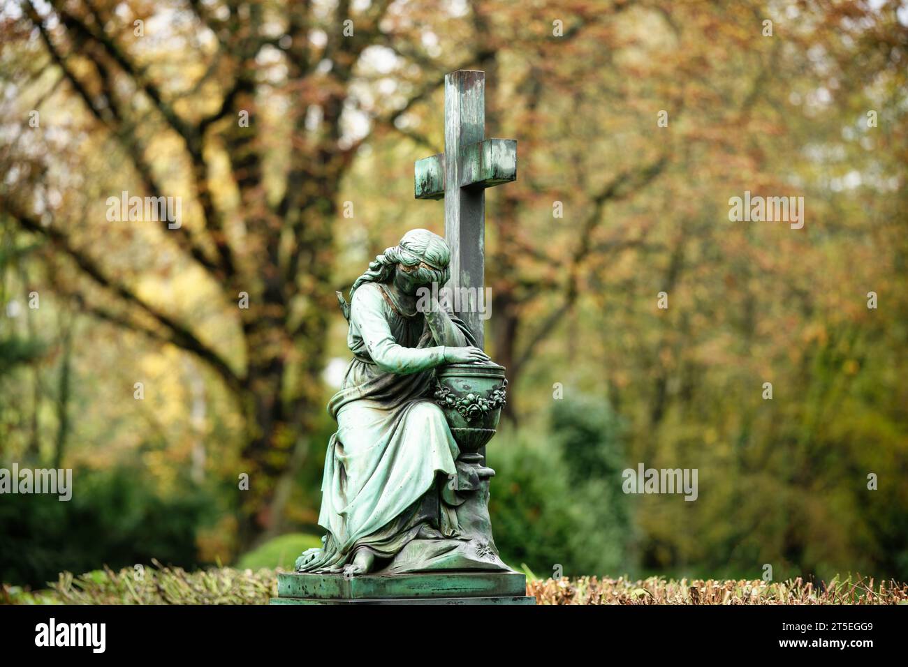 a female funerary figure sits mournfully at the foot of a cross with an ...
