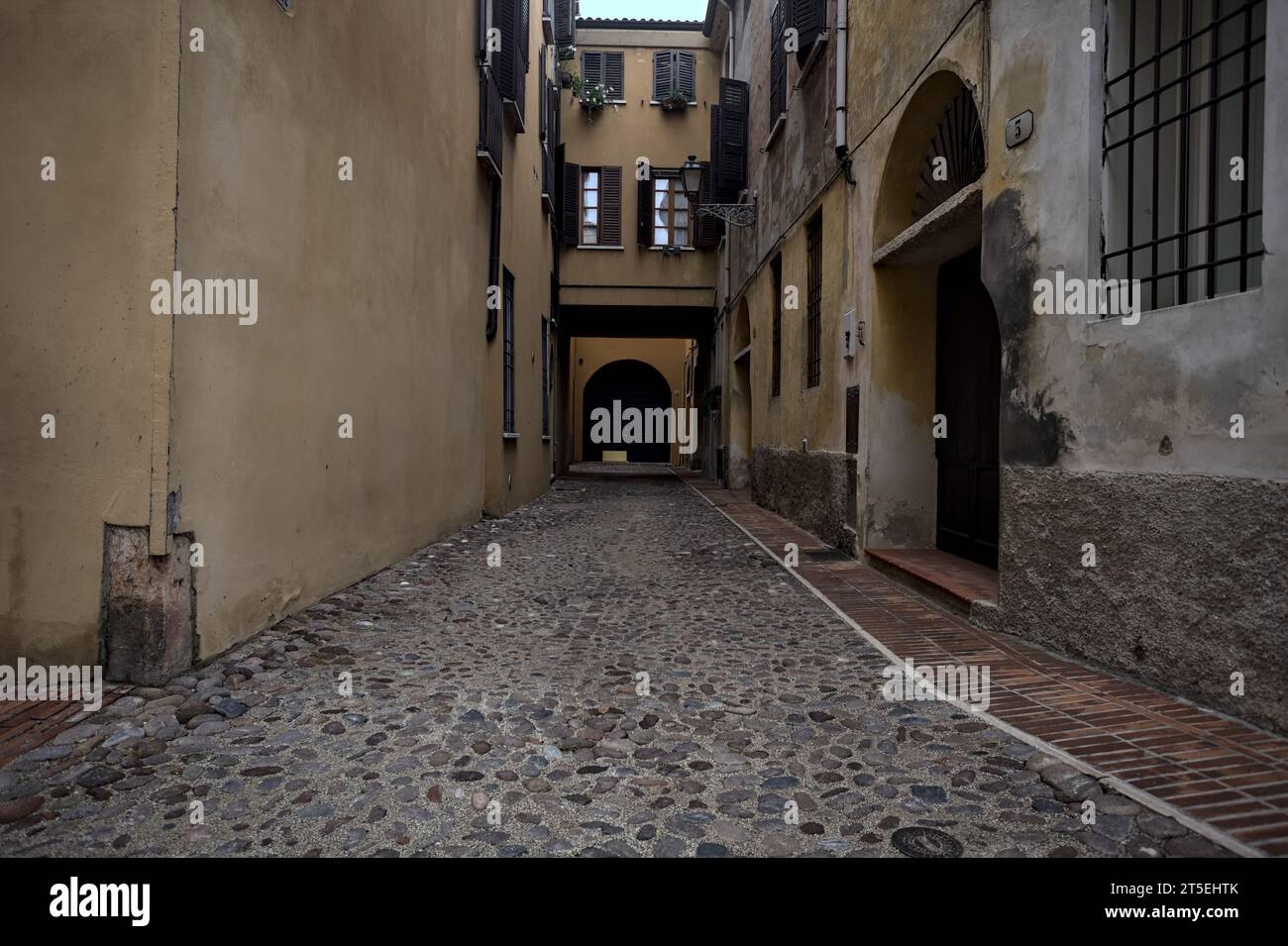 Cobbled and narrow alley between buildings on a cloudy day in an ...