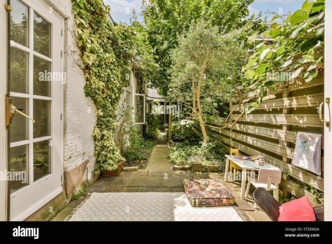 a back yard with lots of plants on the walls, and an open door leading ...