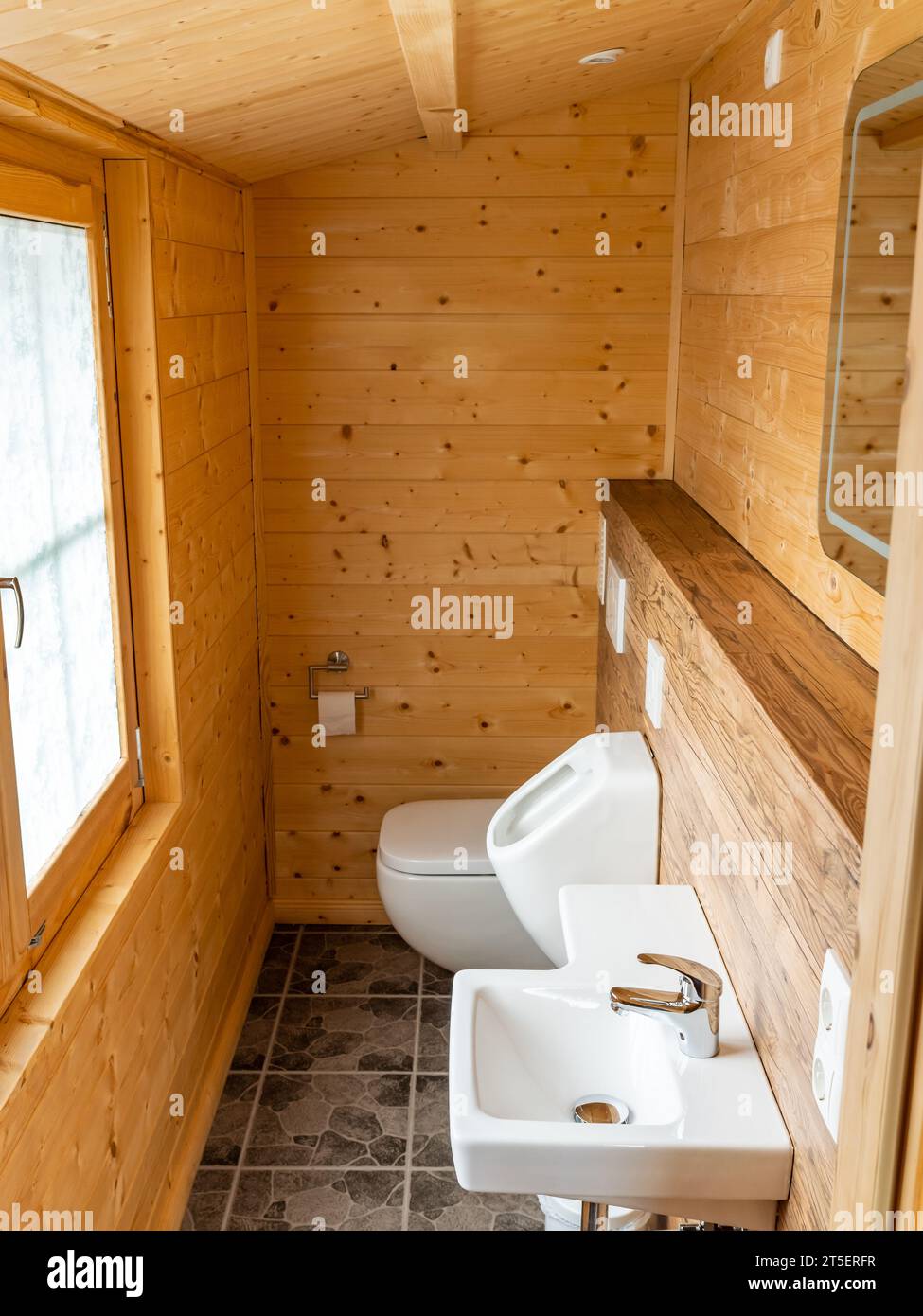 Bathroom in a wooden building. White sink, urinal and toilet. Interior ...