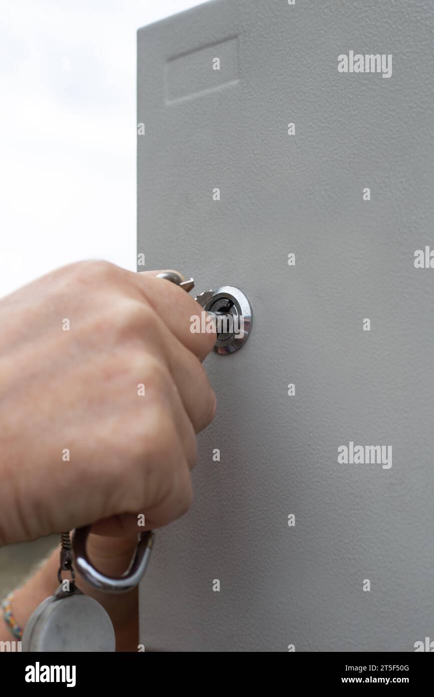 a man closes the lock on the electrical panel cover. Security of power ...