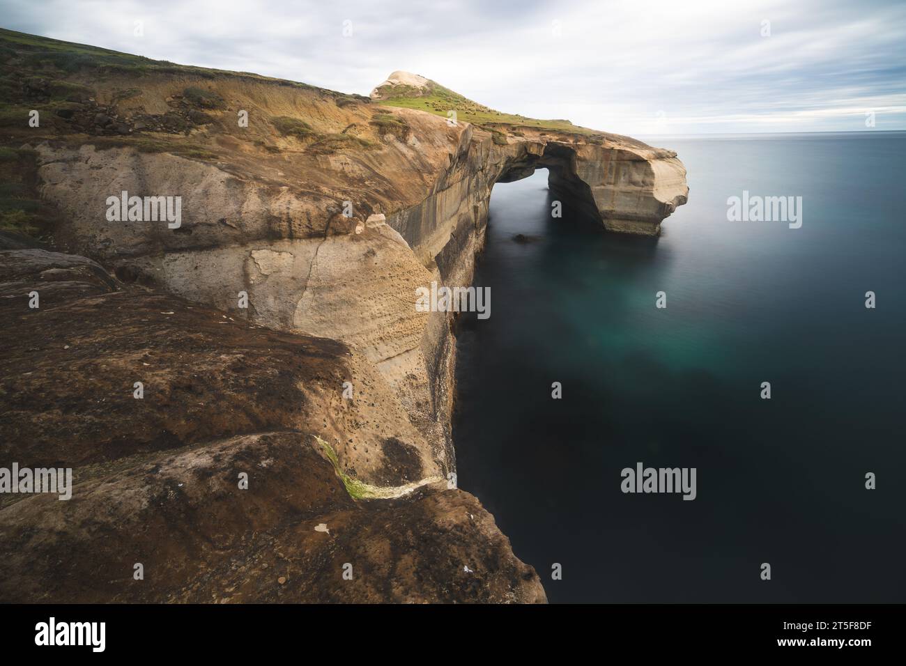 A stunning landscape featuring an imposing arch situated on a rugged ...