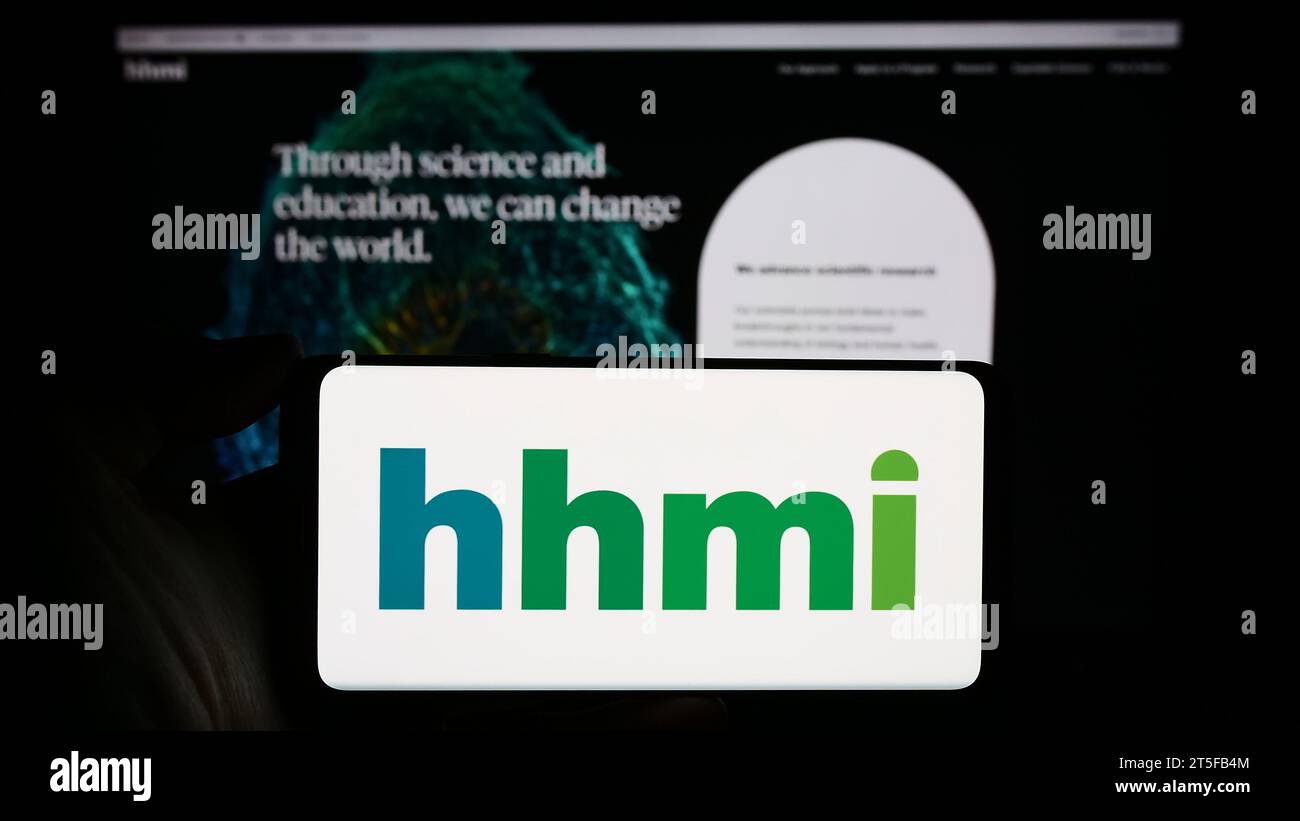 Person holding mobile phone with logo of US foundation Howard Hughes ...